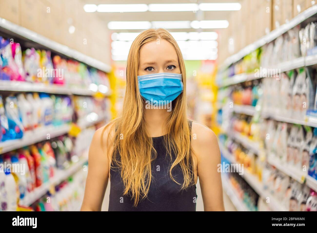 Alarmed female wears medical mask against coronavirus while grocery ...