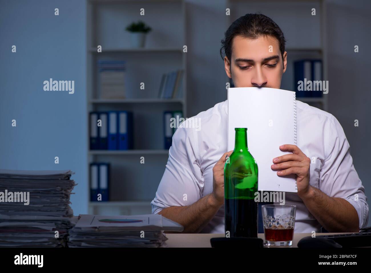 Alcohol addicted businessman working late Stock Photo - Alamy