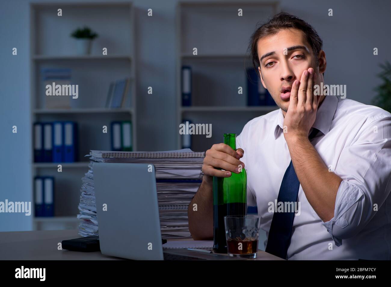 Alcohol addicted businessman working late Stock Photo - Alamy