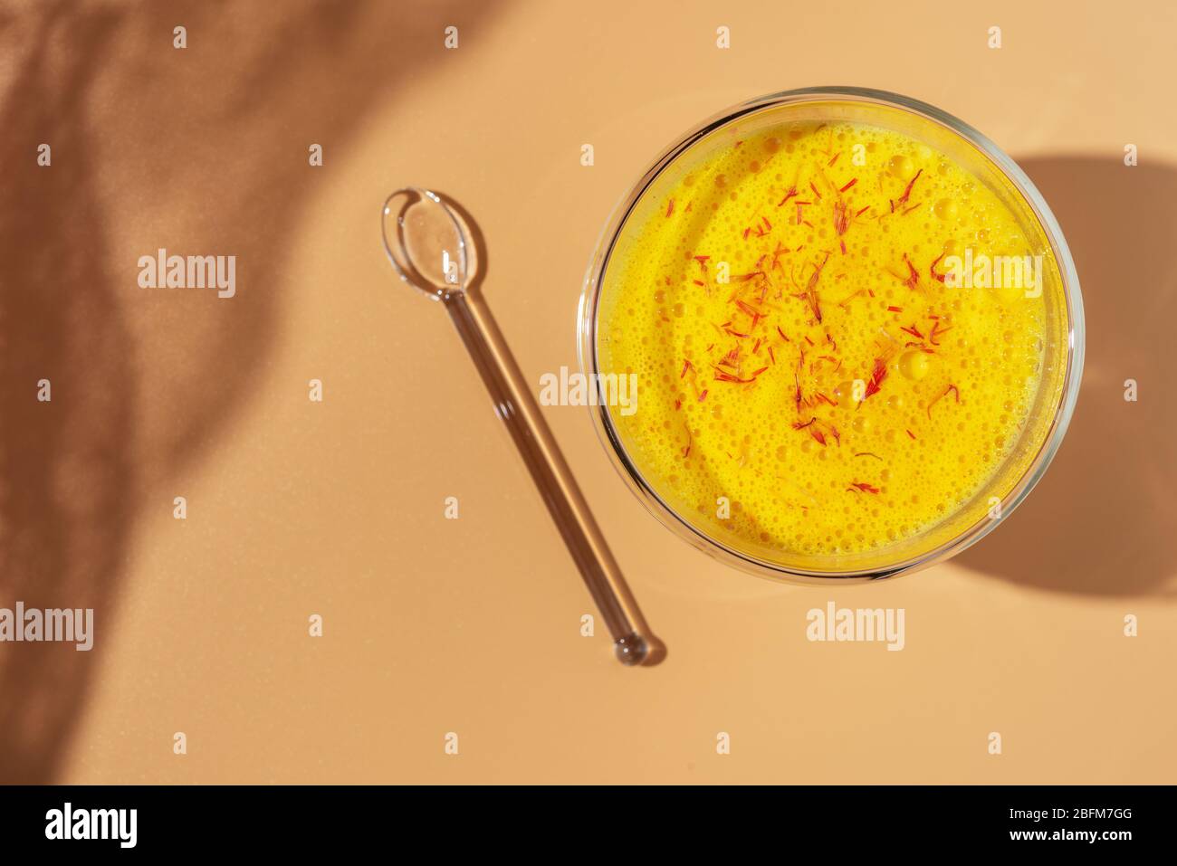 Saffron latte in a glass cup on a beige background, golden milk, hard ...