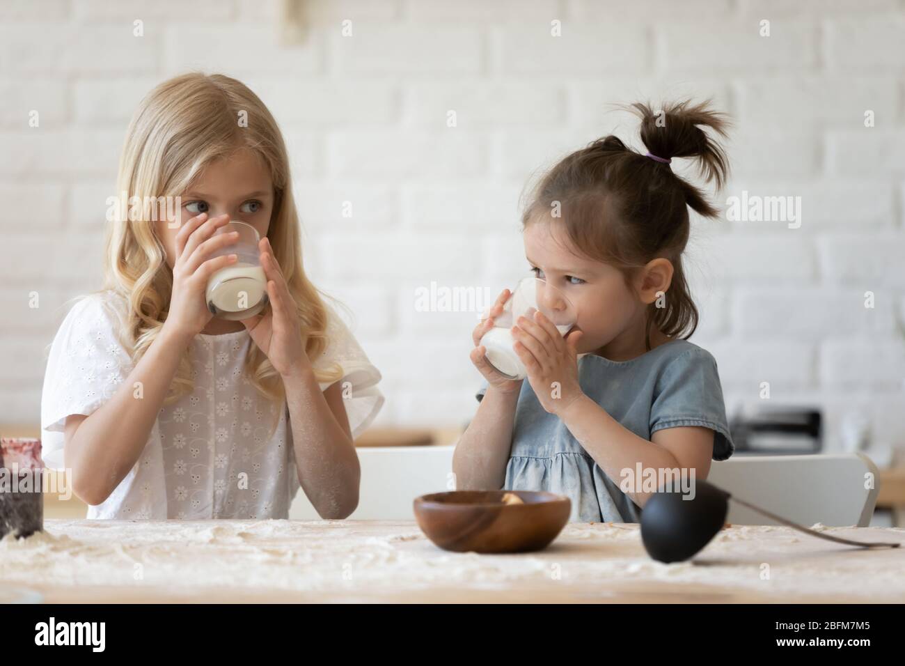 Close up smiling little sisters drinking milk Stock Photo - Alamy