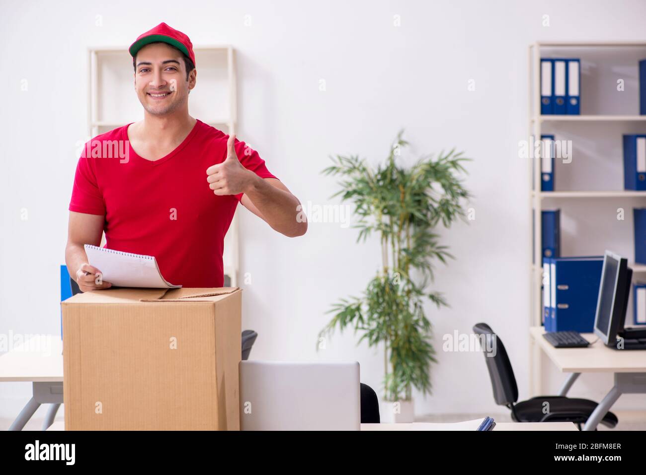 Young courier delivering postbox to the office Stock Photo - Alamy