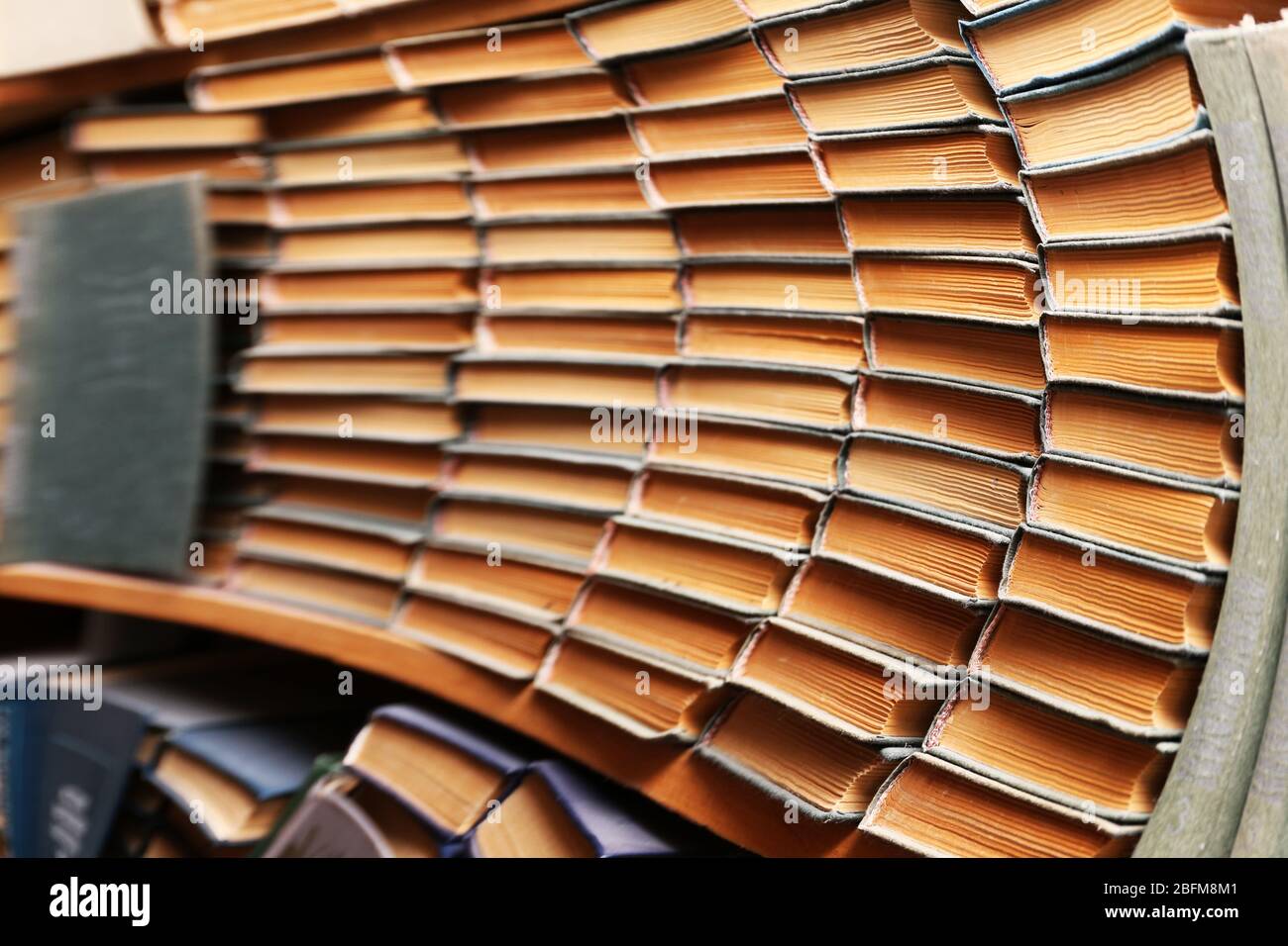 Many books on bookshelf in library, image with perspective distortion ...