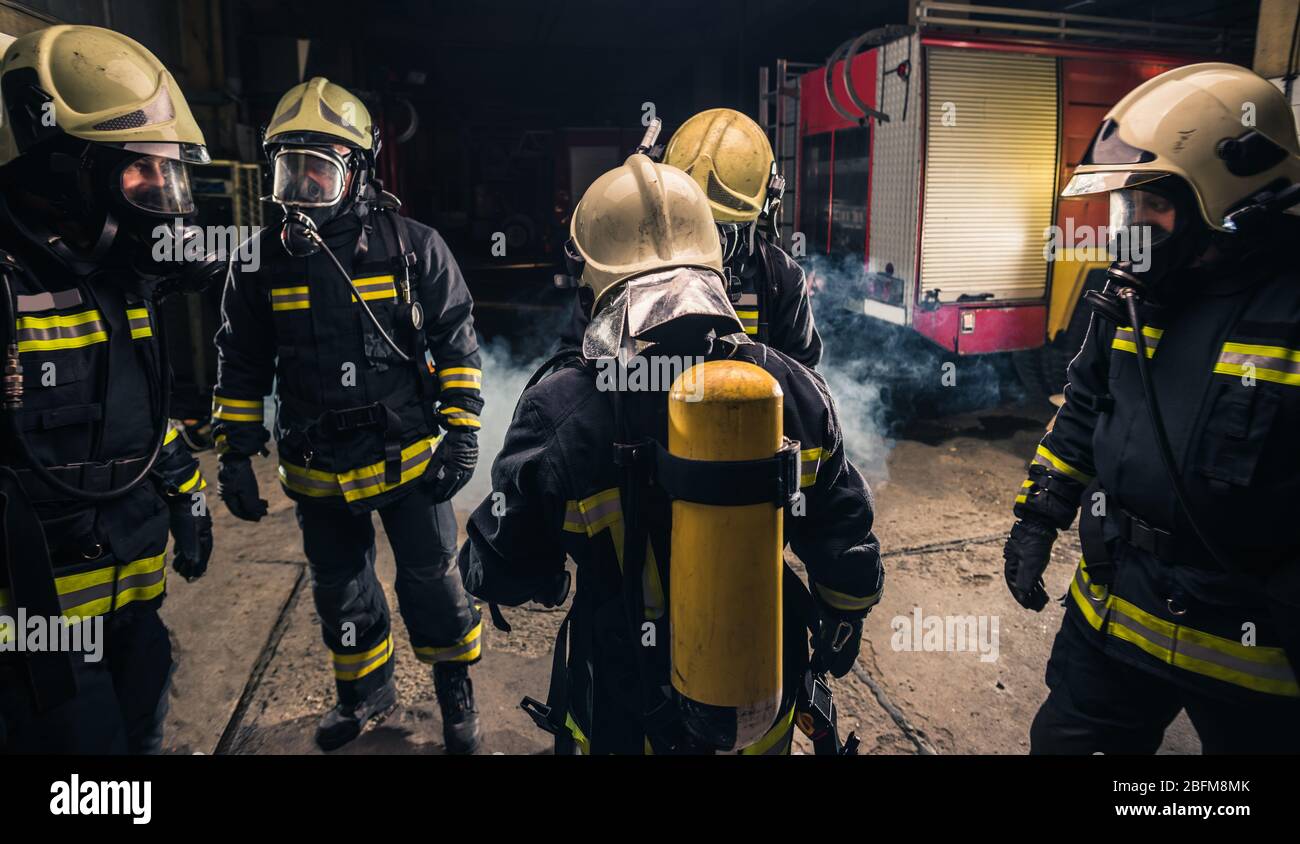 Group of firefighters in the fire department checking their gas mask ...