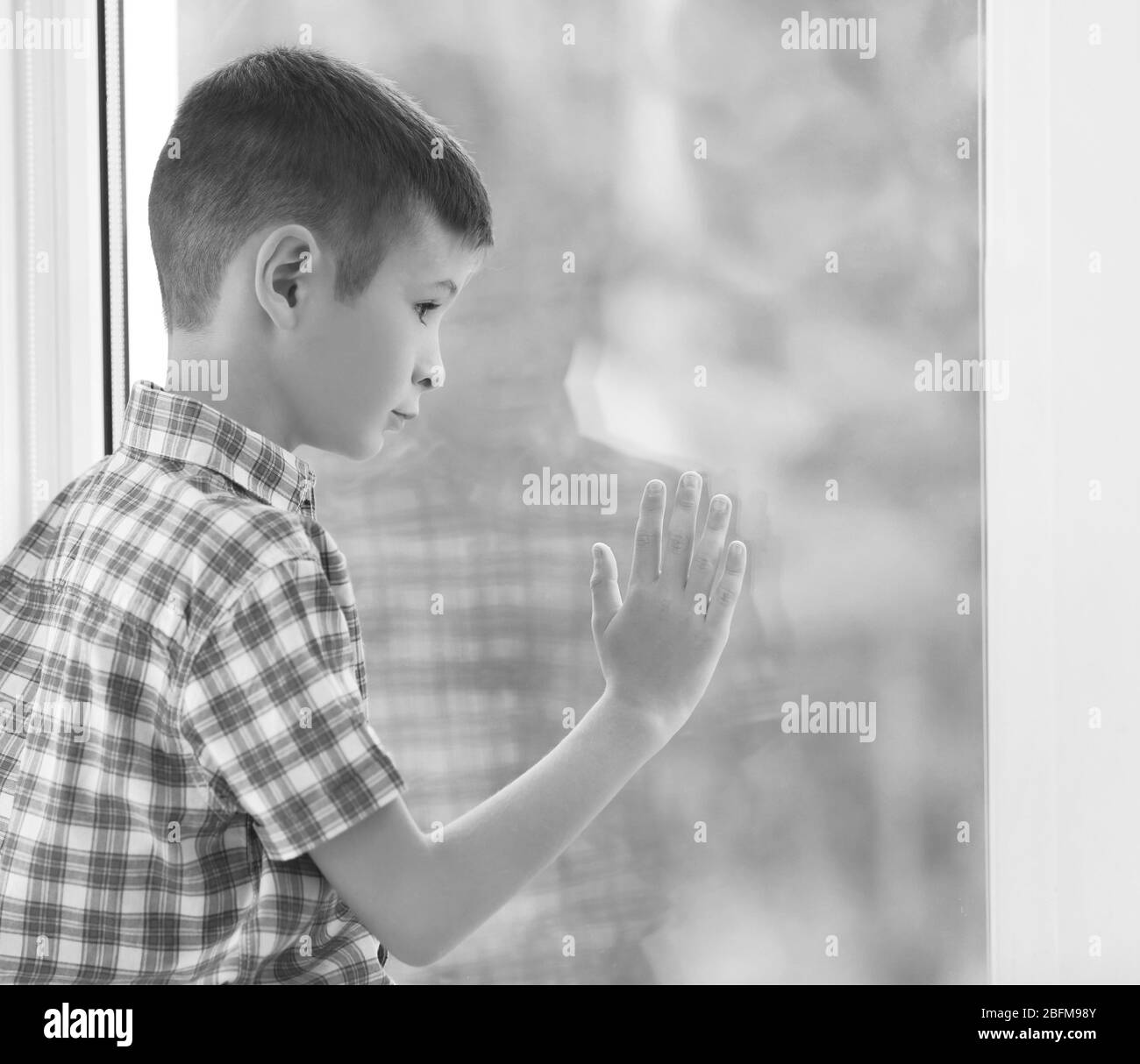 Sad boy sitting near window Stock Photo - Alamy