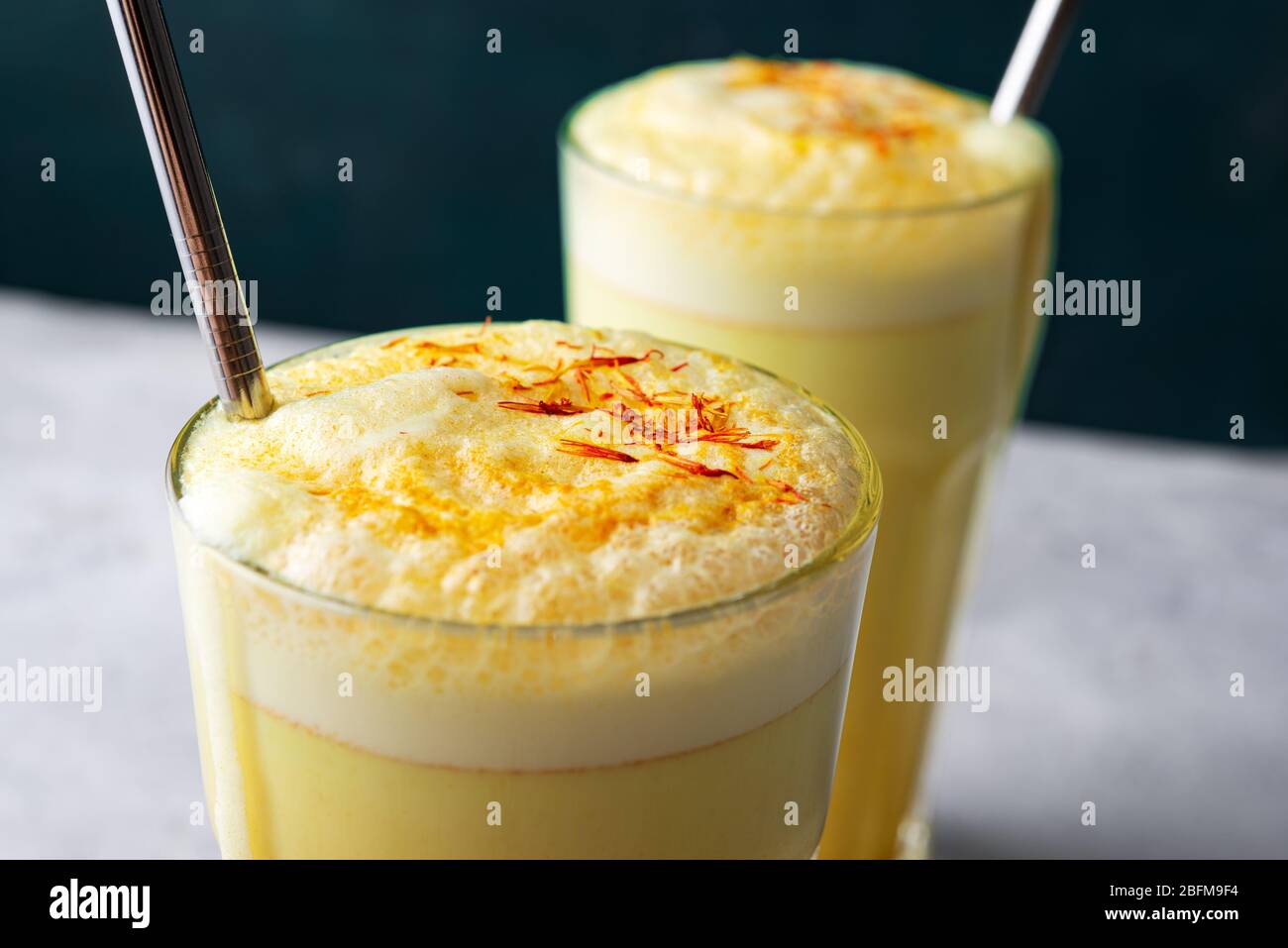 Saffron latte in a glass cup on concrete background,metal straw,dry ...
