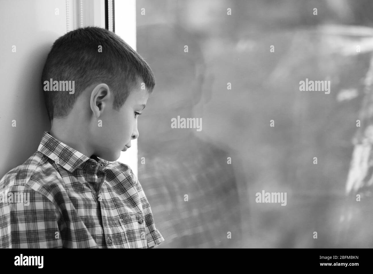 Sad boy sitting near window Stock Photo - Alamy