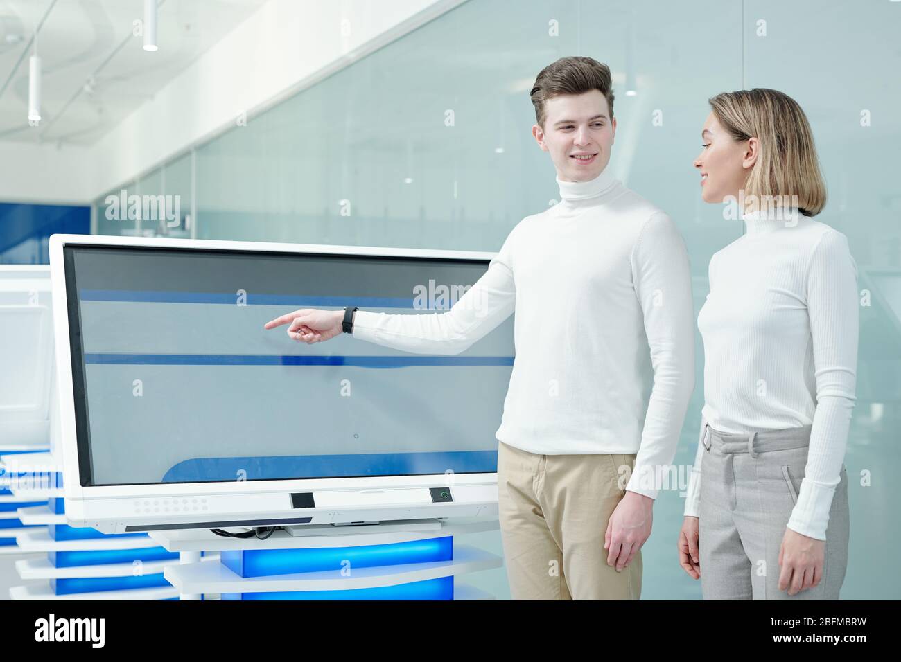 Happy young intelligent man looking at his colleague or customer while ...