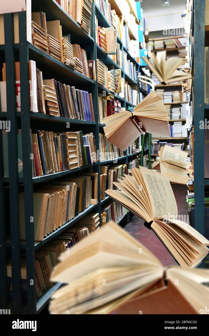 Flying books on library bookshelves background Stock Photo - Alamy