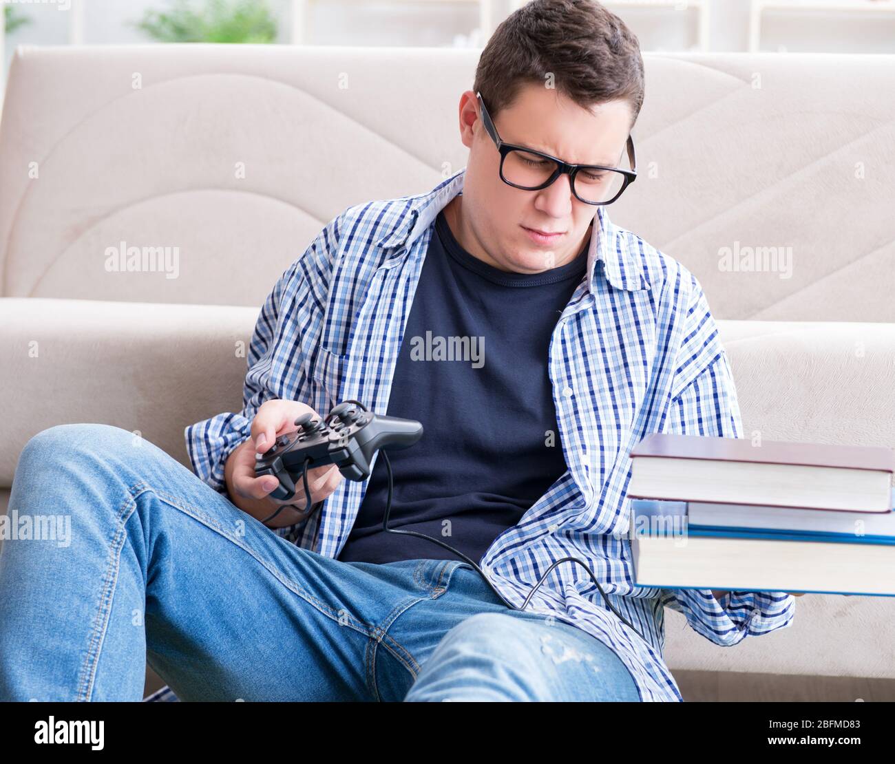 The young student trying to balance studying and playing games Stock ...