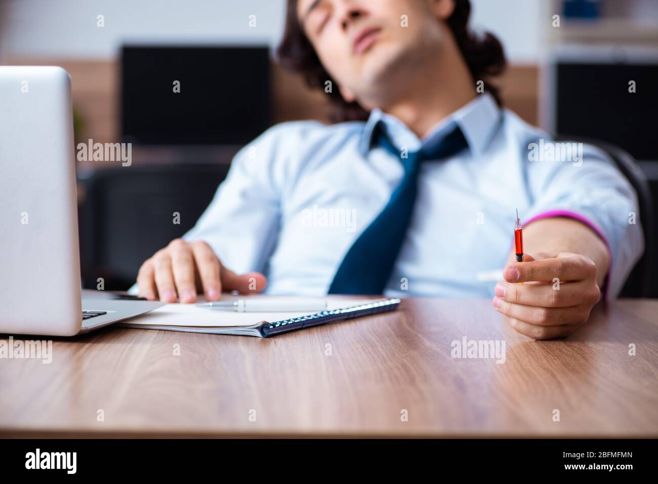 The young man having problems with narcotics at workplace Stock Photo ...