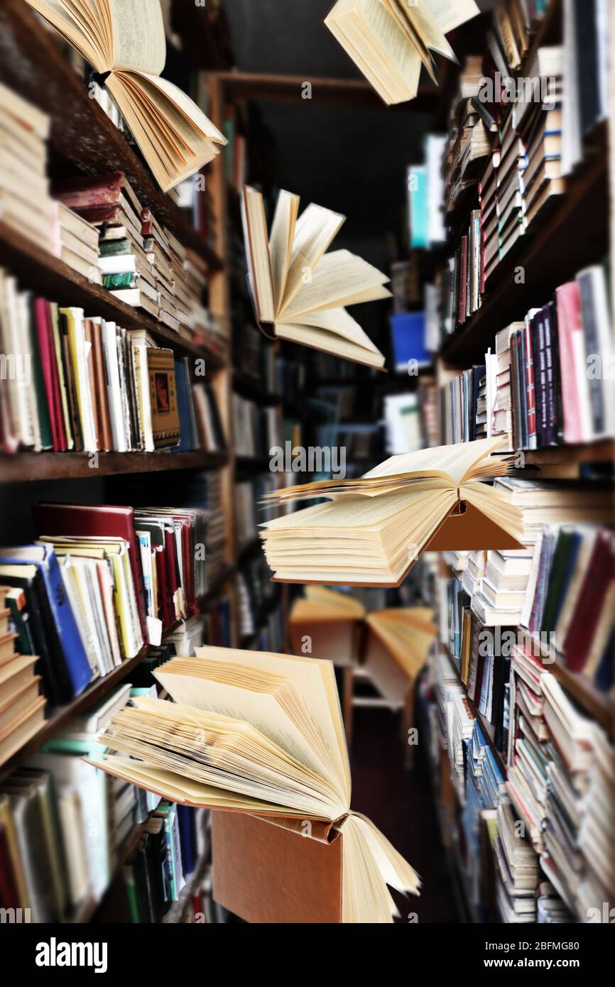 Flying books on library bookshelves background Stock Photo - Alamy