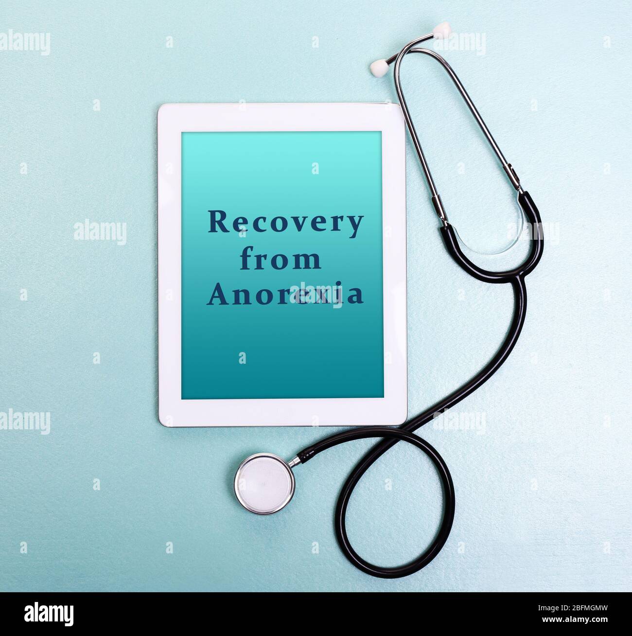 Tablet pc and text Recovery from Anorexia on screen on light blue ...