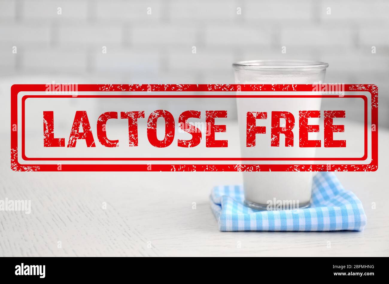 Glass of milk on wooden table and lactose free sign, on bricks wall ...