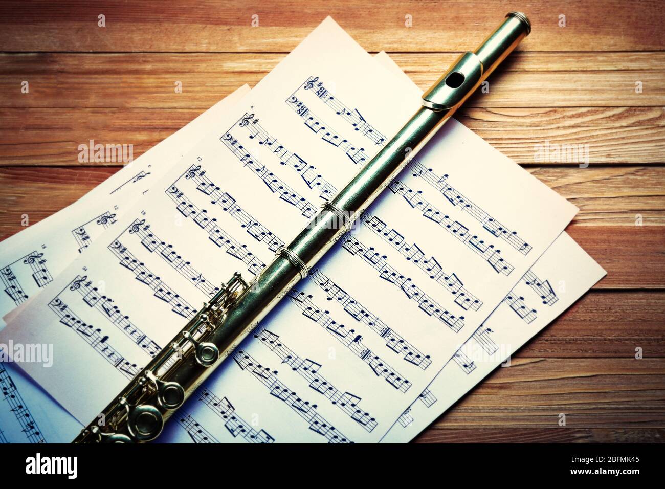Flute on musical notes and on wooden table background Stock Photo - Alamy