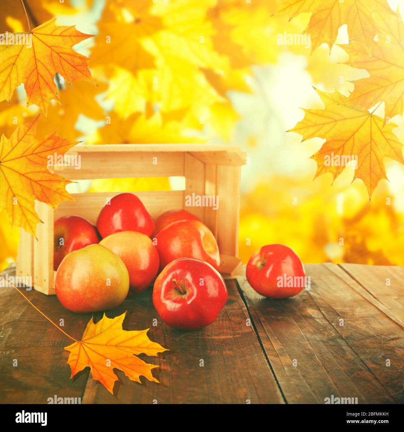 Spilled red apples near crate on nature background Stock Photo - Alamy