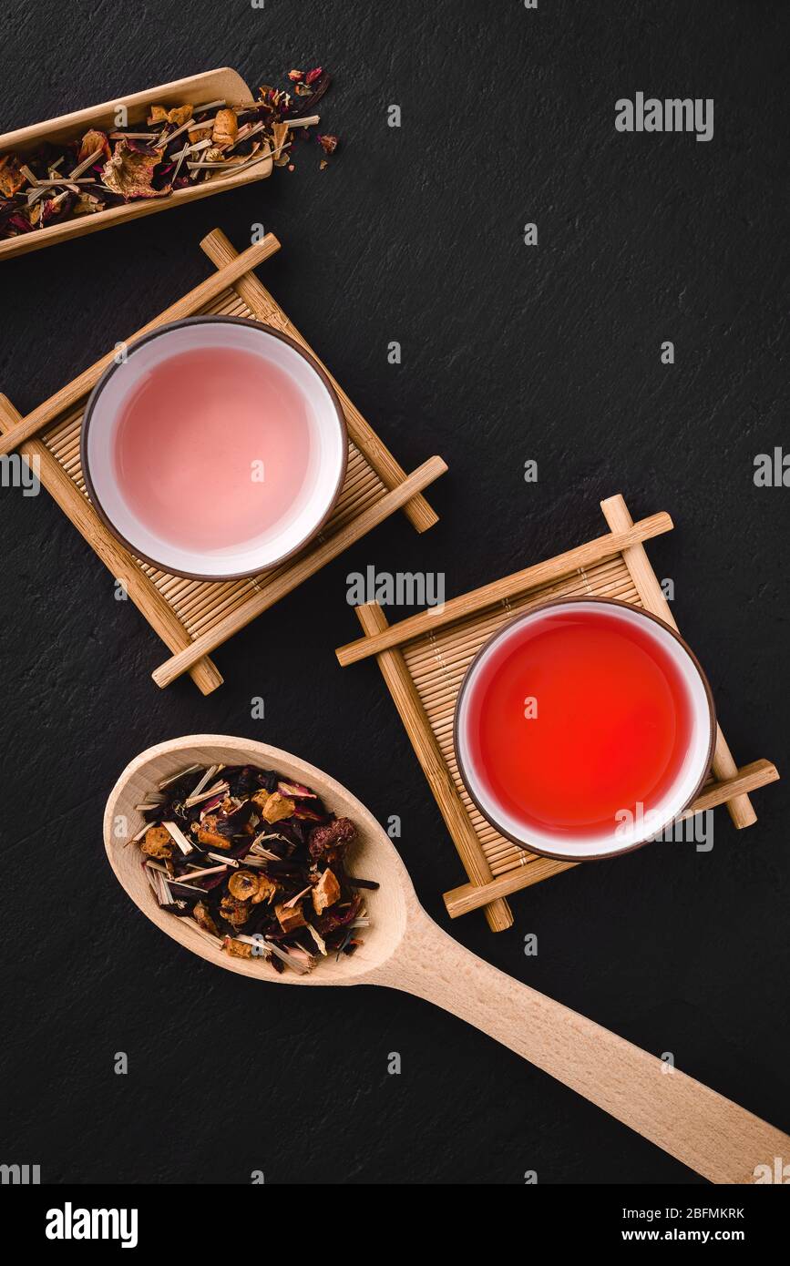 A set of different aromatic natural red fruit tea in tree bowls, wooden ...
