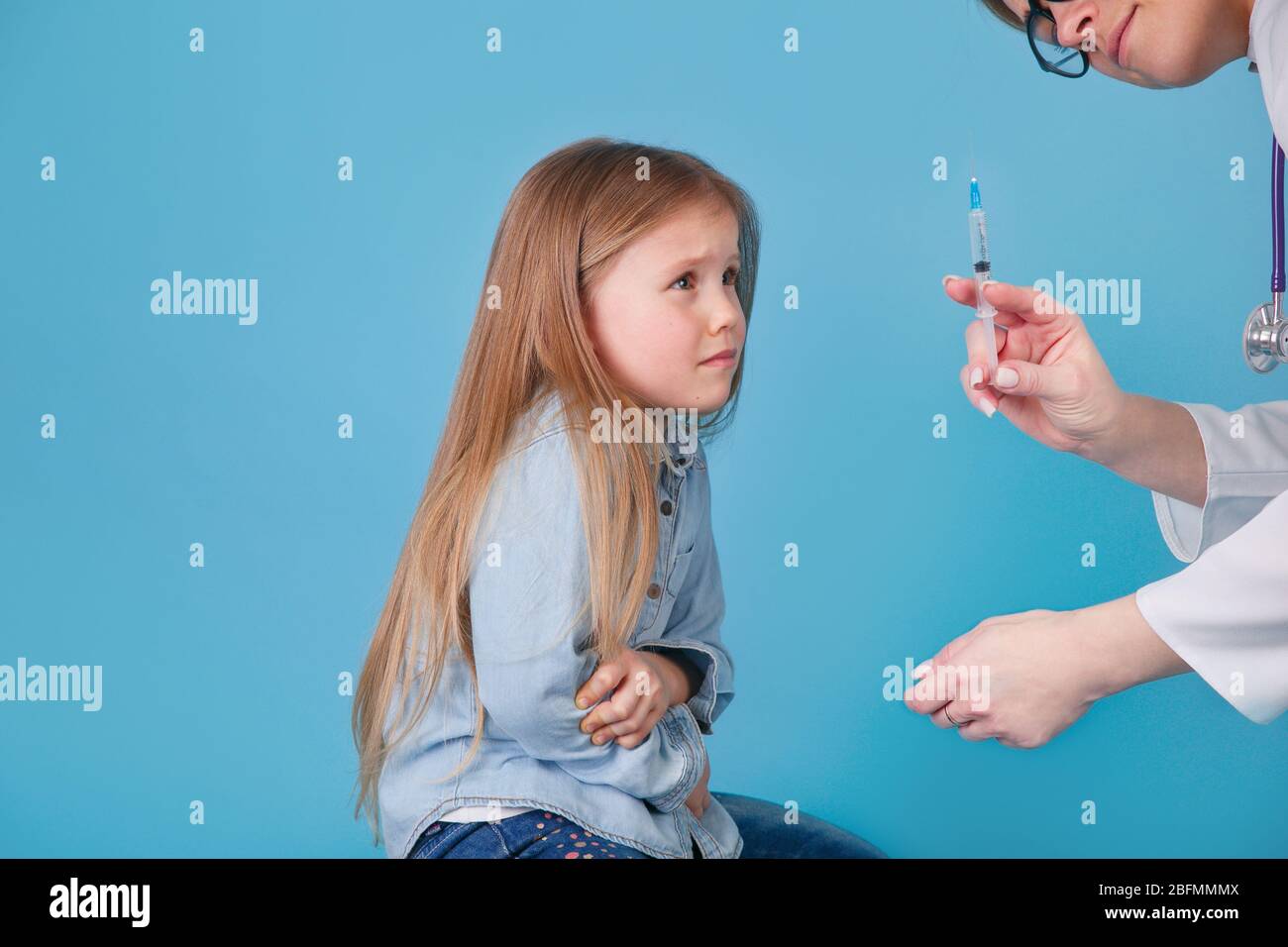 Frightened baby girl before an injection on blue background Stock Photo ...