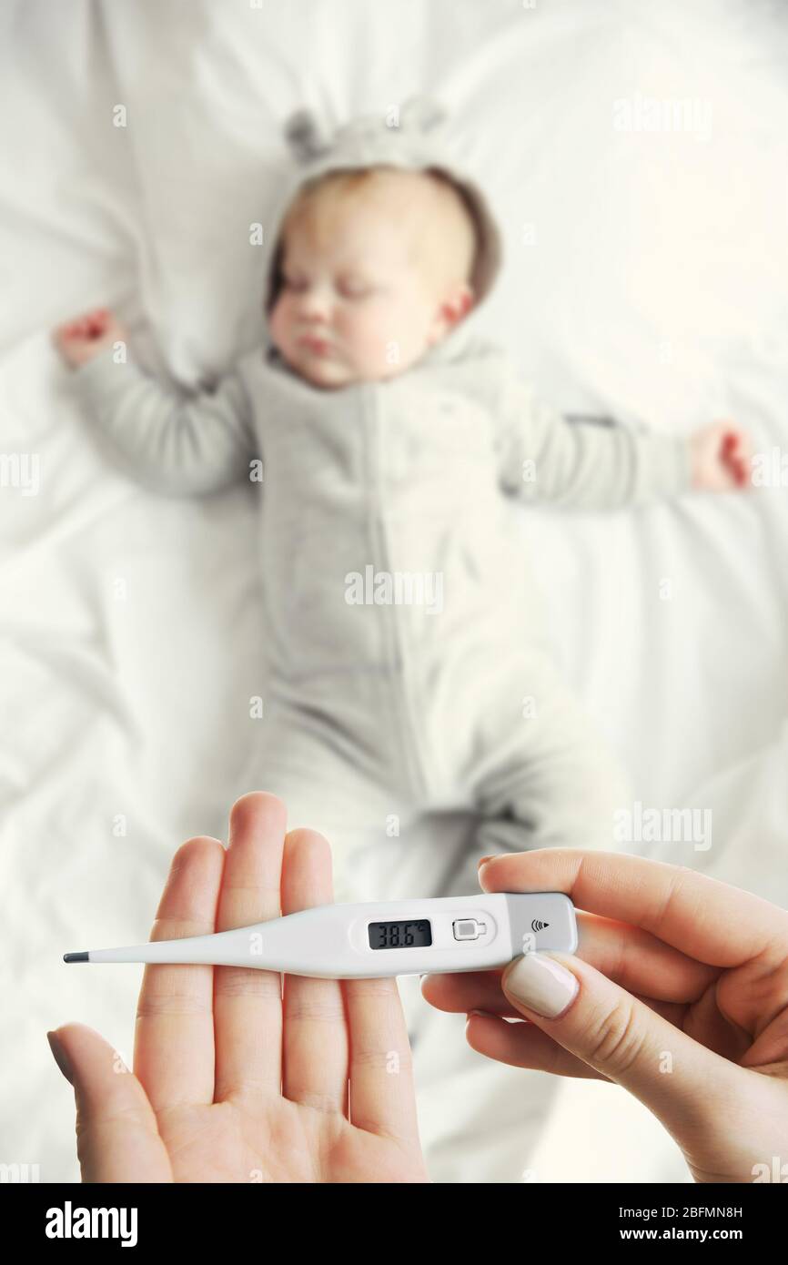 Loving baby sleeping on soft bed and hand with thermometer Stock Photo ...