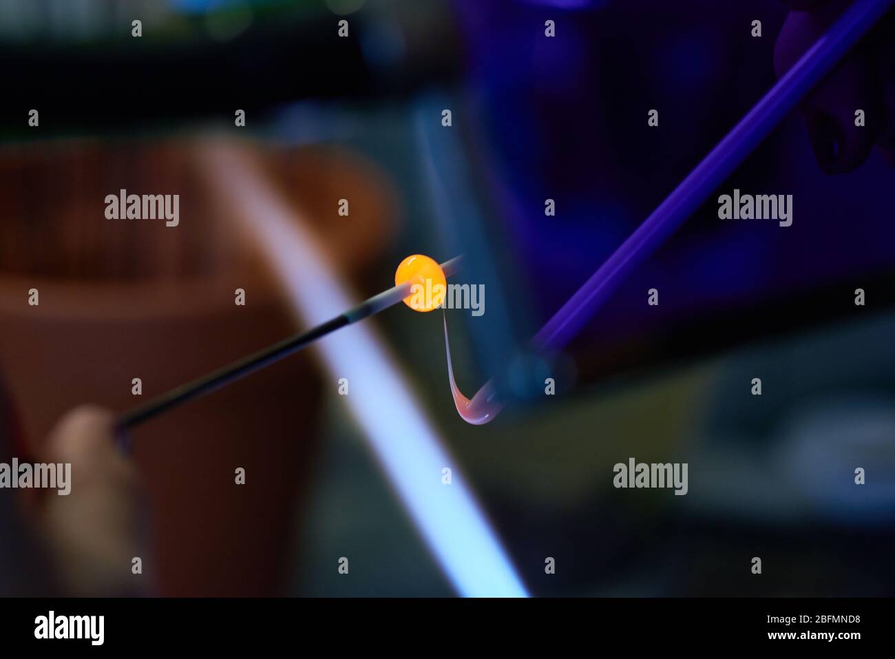 Glass stick workpiece held by lampworking master in process of burning ...