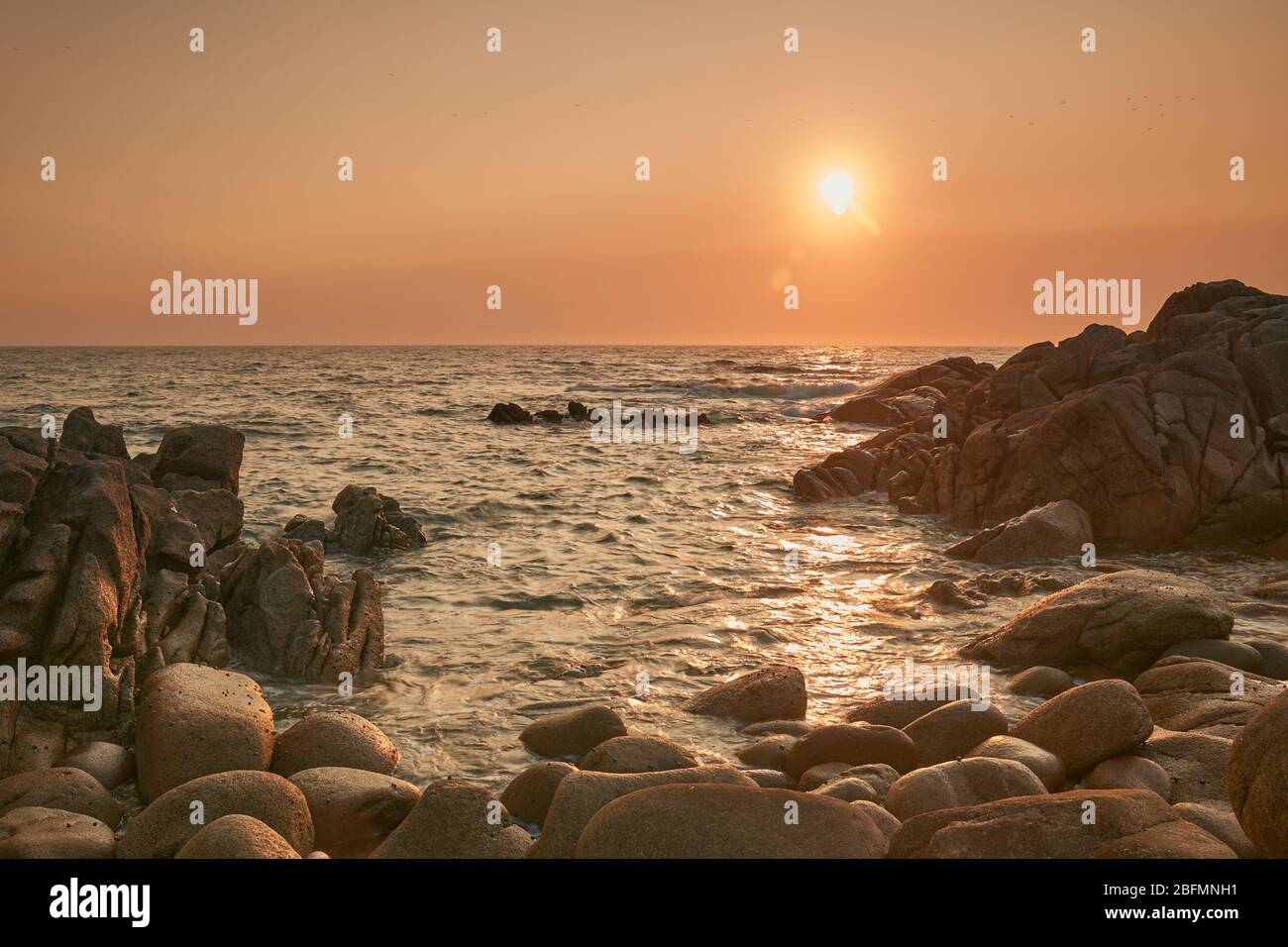 Sunset over rocks rounded by wave erosion Stock Photo - Alamy