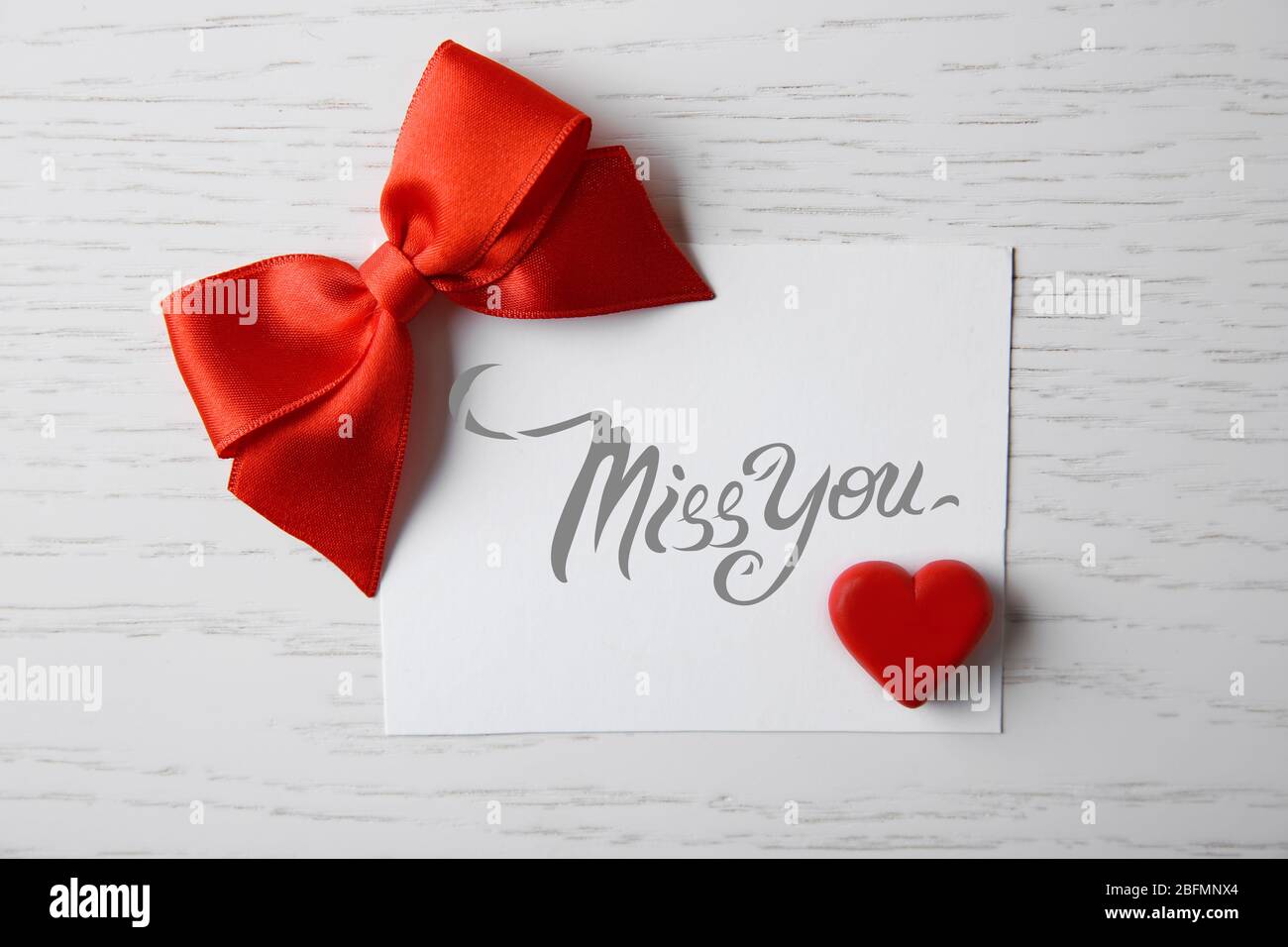 Blank present card with ribbon bow and small heart on wooden background ...