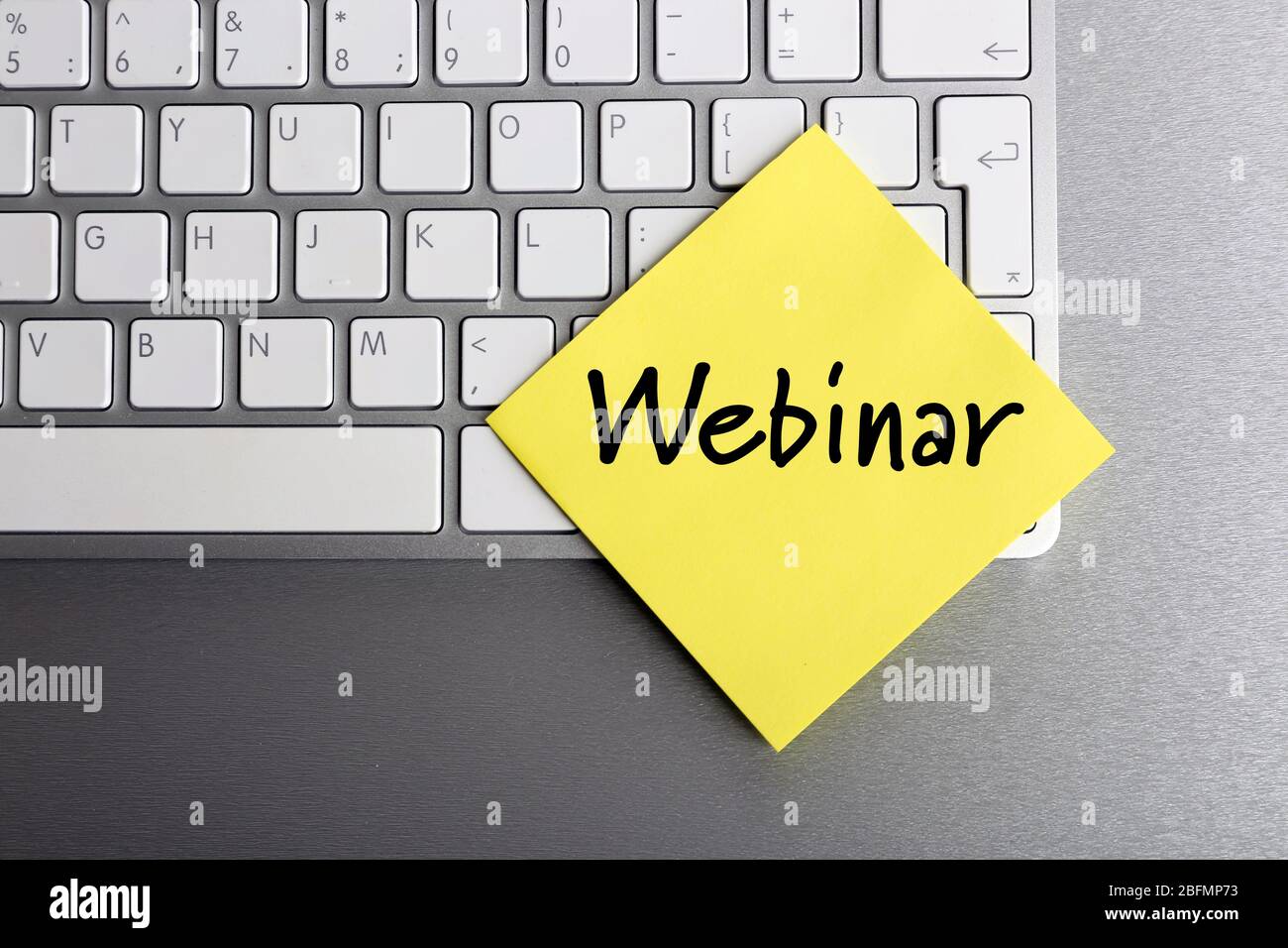 Webinar written on sticky note on laptop keyboard Stock Photo - Alamy