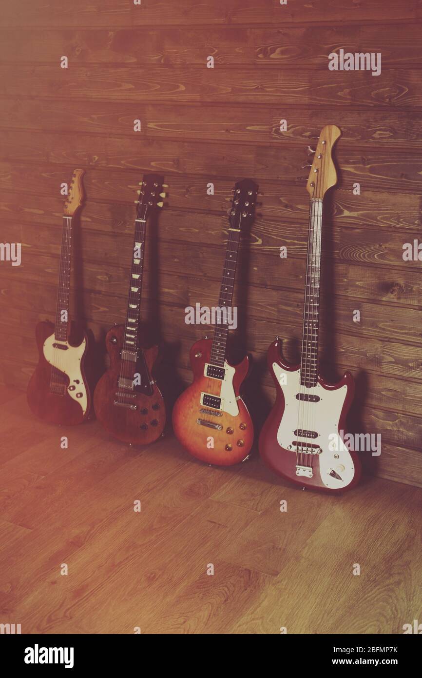 Four electric guitars on wooden background Stock Photo - Alamy