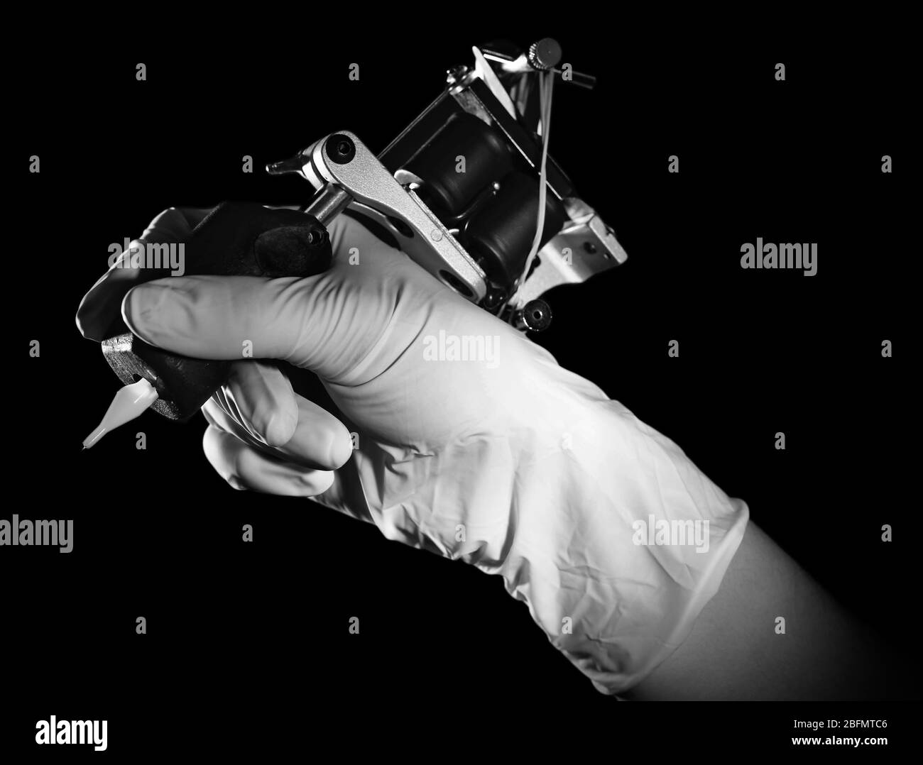 Tattoo artist holding tattoo machine, on dark background. Retro ...