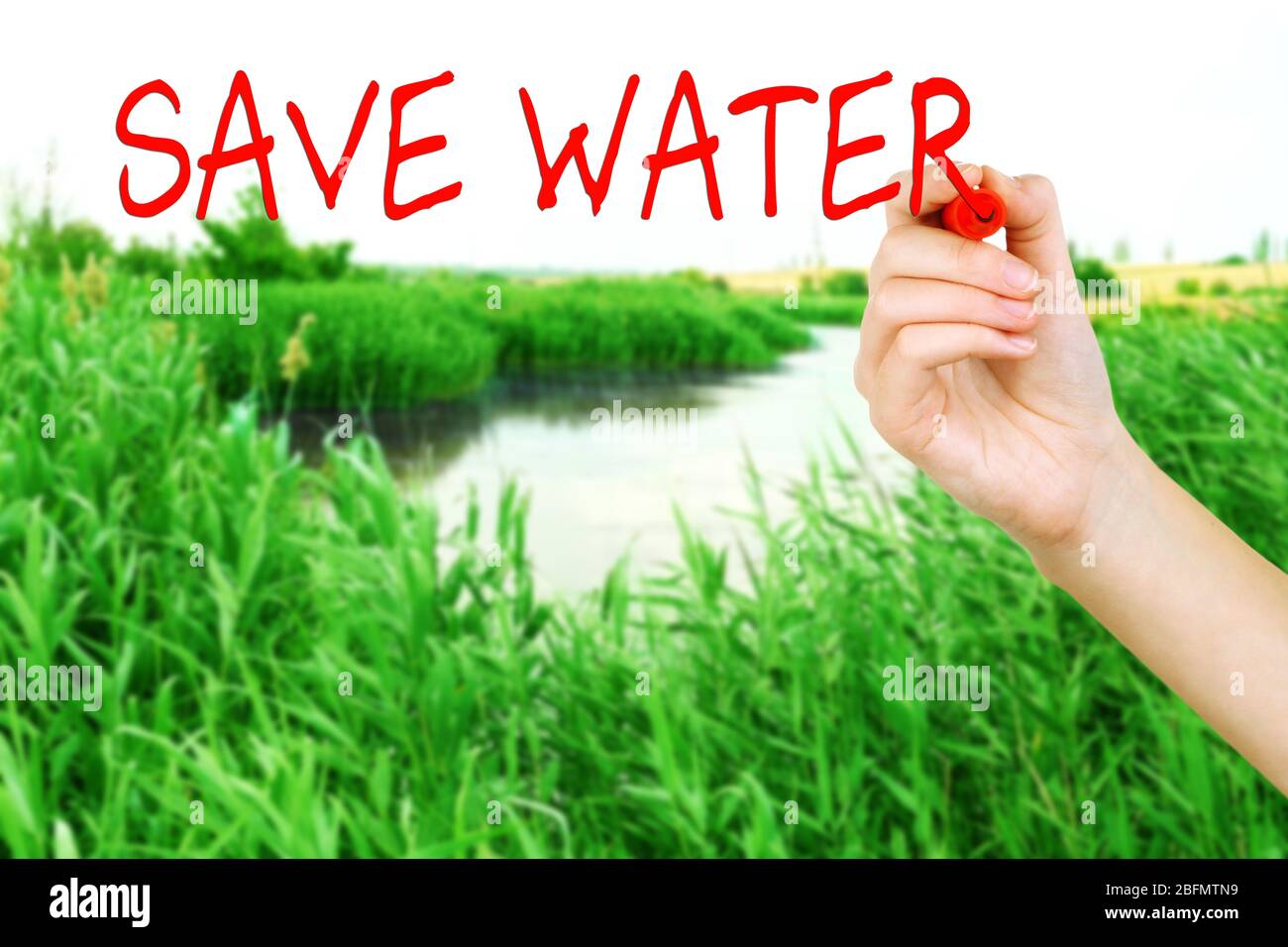 Female hand with felt-tip pen and Save Water text on lake background ...