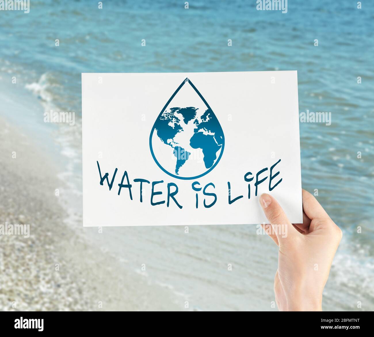Save Water text on piece of paper in hand on sea water background Stock ...
