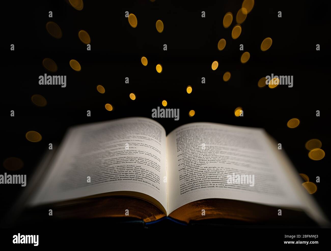 A book with gold edges is highlighted with glowing star lights in the ...