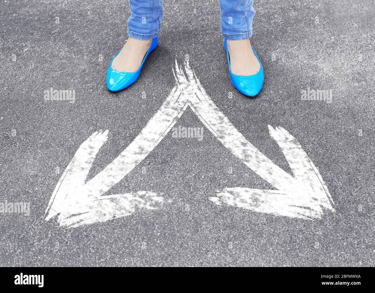 Female feet standing on road with white arrows Stock Photo - Alamy