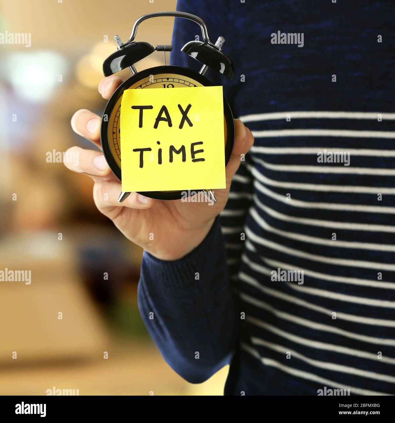 Tax concept. Man holding alarm clock, tax time Stock Photo - Alamy