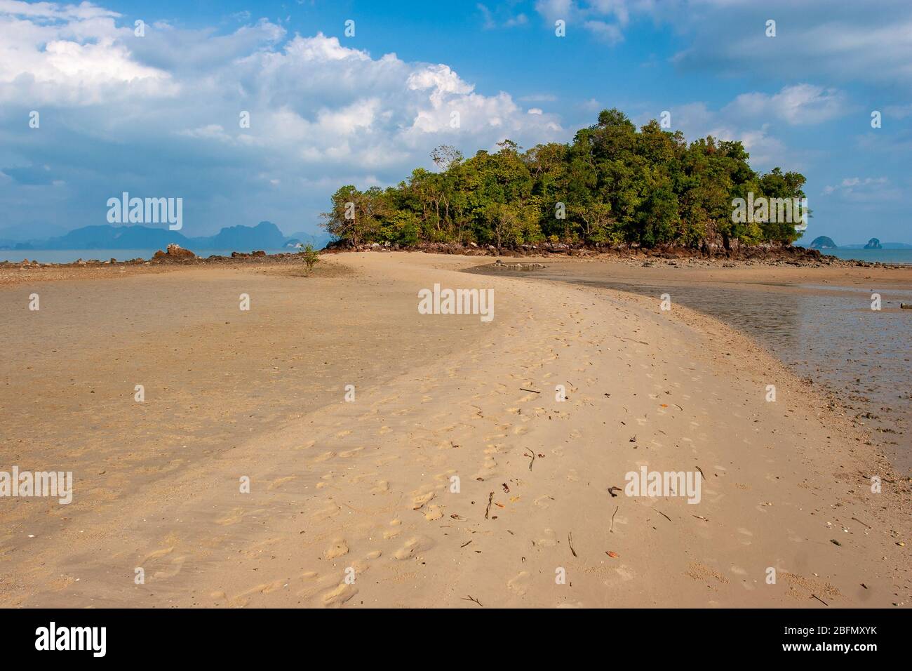 The sand spit to the island opened at low tide. Green trees on the ...