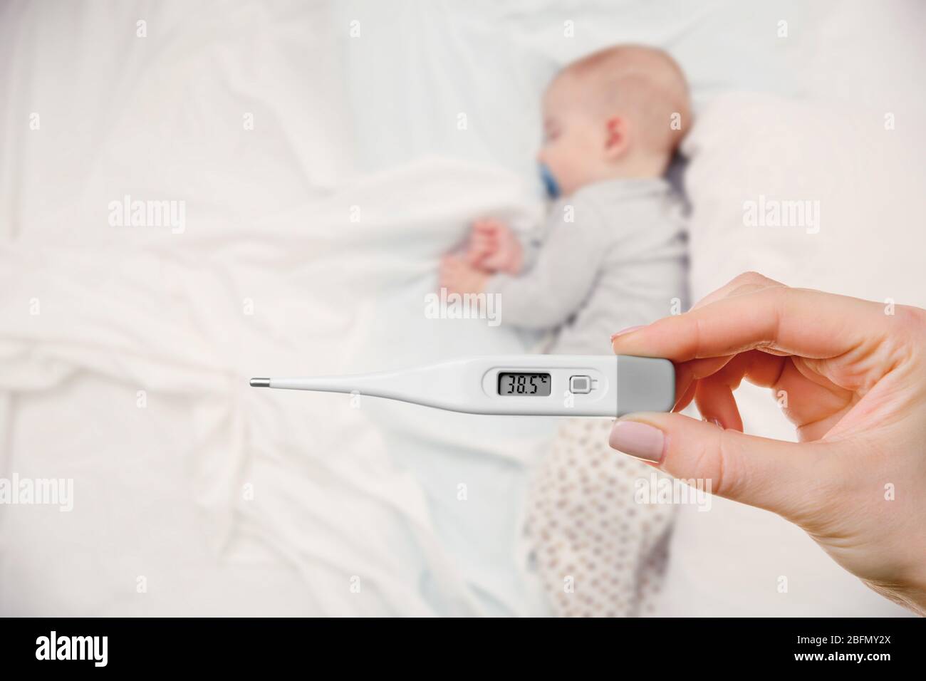 Loving baby sleeping on soft bed and hand with thermometer Stock Photo ...