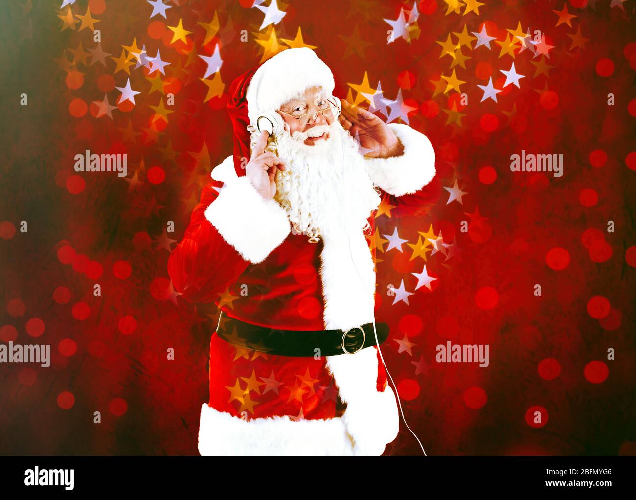 Santa Claus listening to music with headphones against abstract red ...