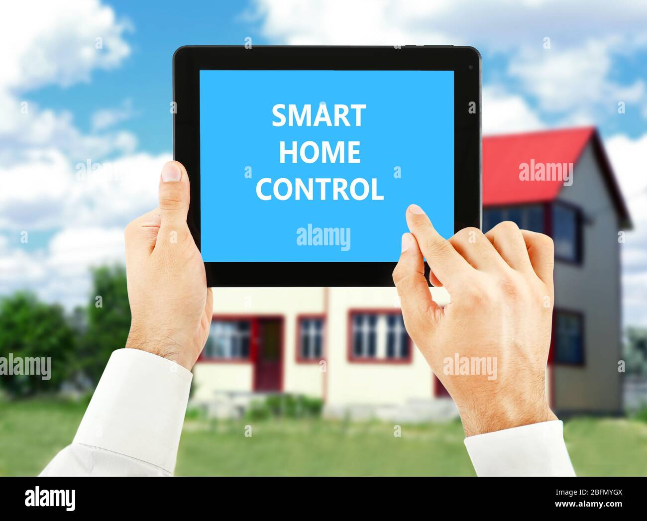 Smart home control concept. Tablet pc in hands on house background ...