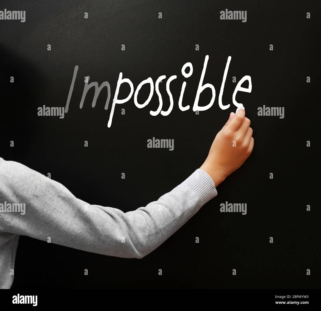 Hand writing word impossible transformed into possible on blackboard ...