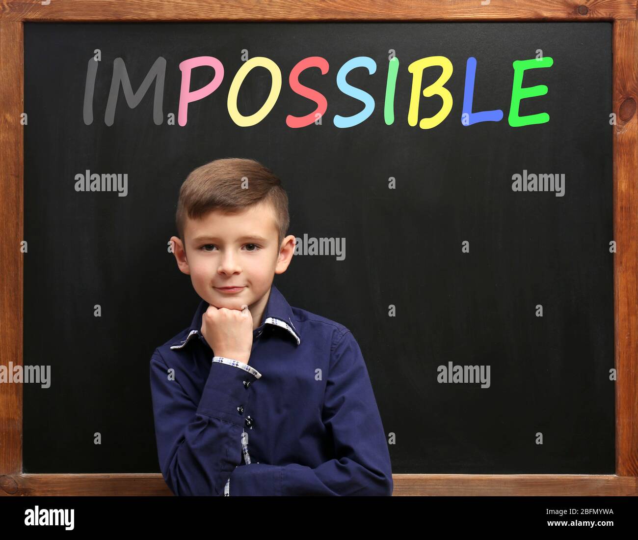Schoolboy near blackboard with word impossible transformed into ...