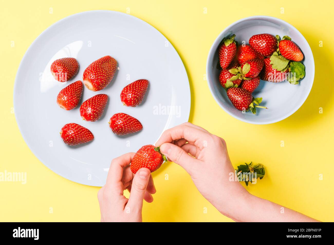 Girl peels strawberries for breakfast. Man's hand holds strawberries on ...
