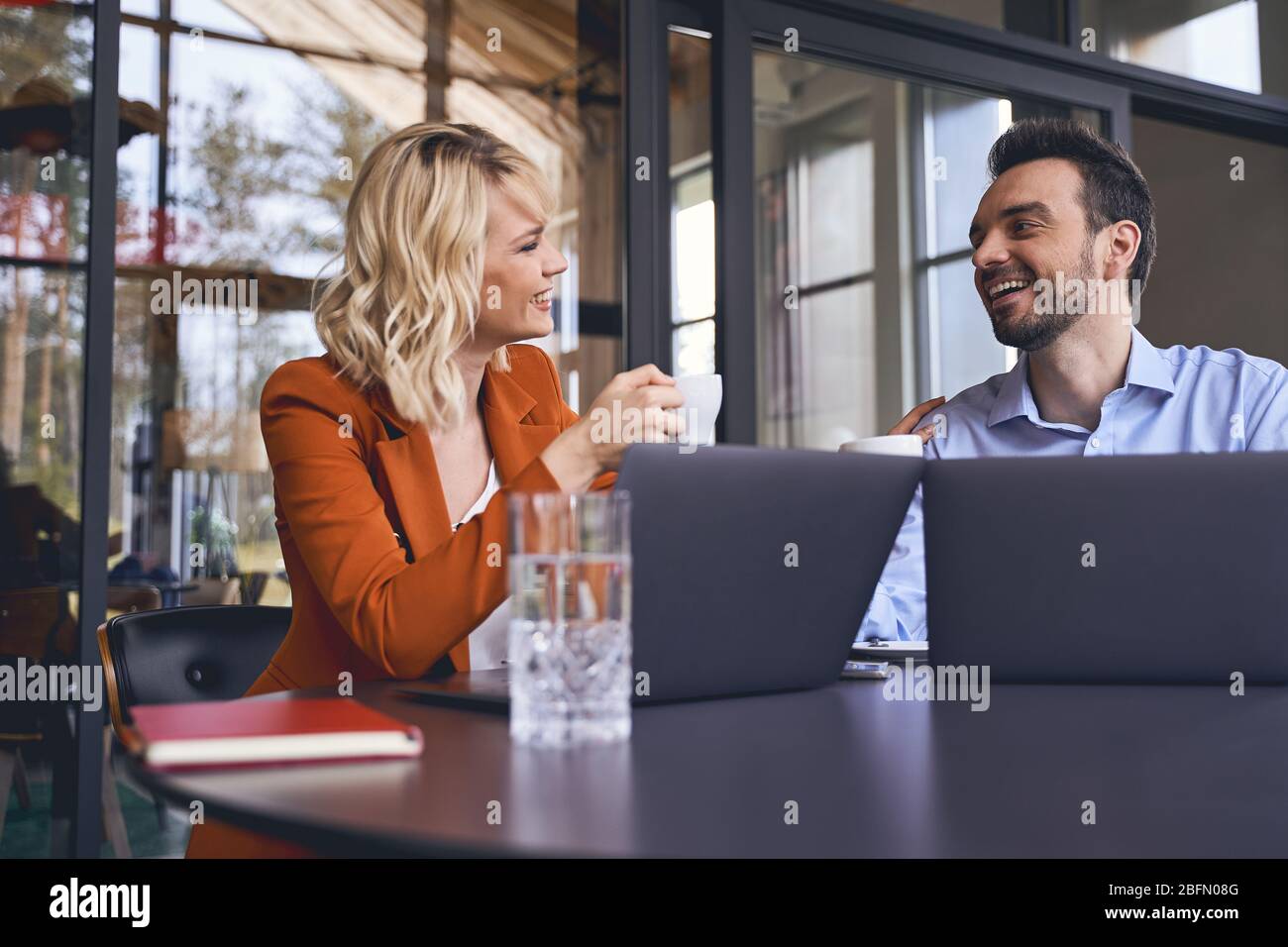 Stylish blonde young manager encouraging her coworker Stock Photo - Alamy