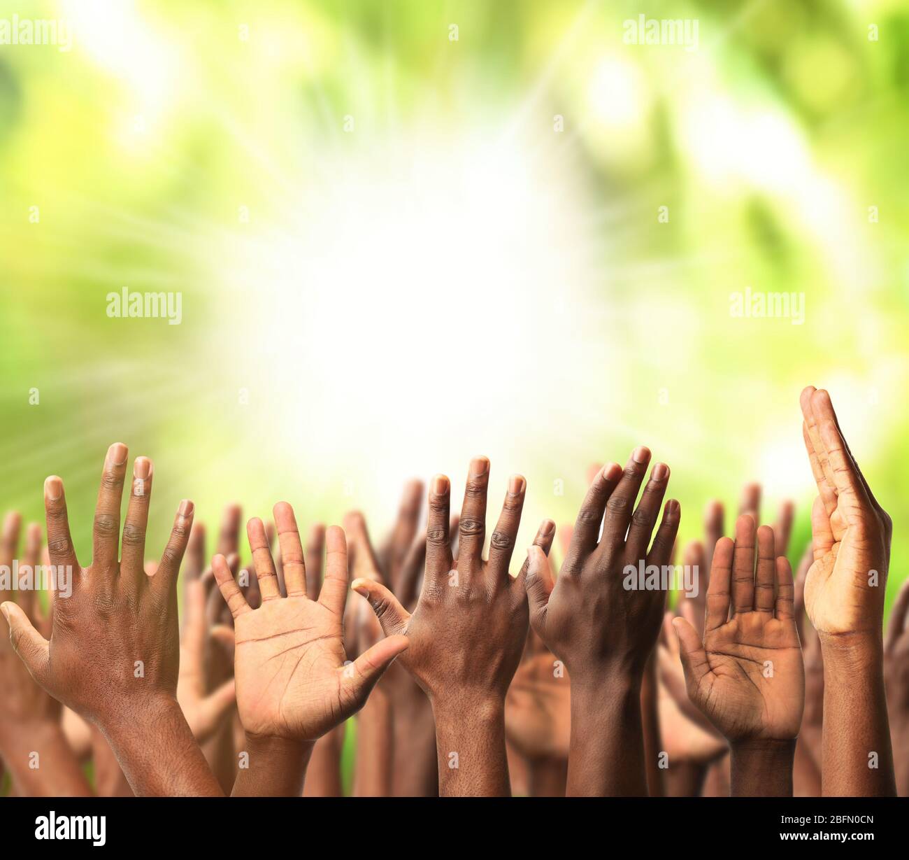 Crowd raising hands on green blurred nature background Stock Photo - Alamy