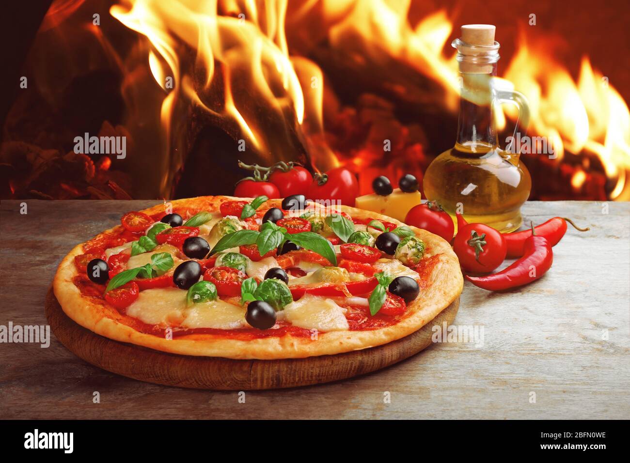 Delicious hot pizza on wooden table against fire flame background Stock ...