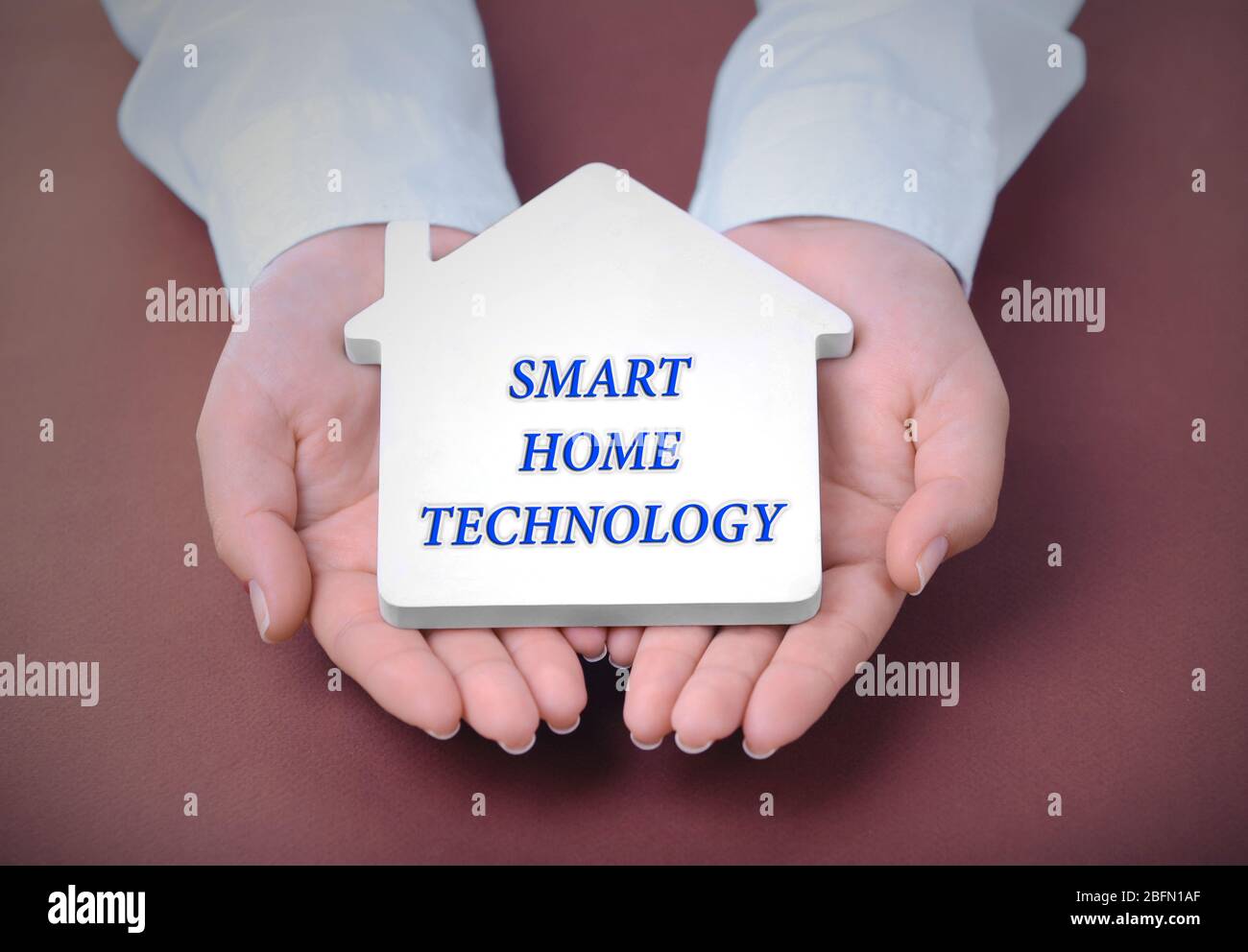 Smart home technology concept. Female hands holding house on brown ...