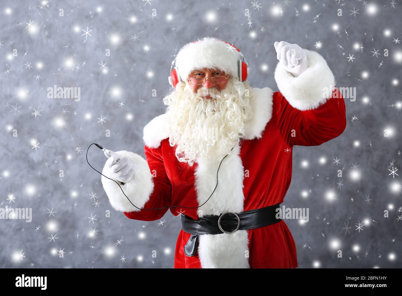 Santa Claus with headphones listening to music on gray wall background ...