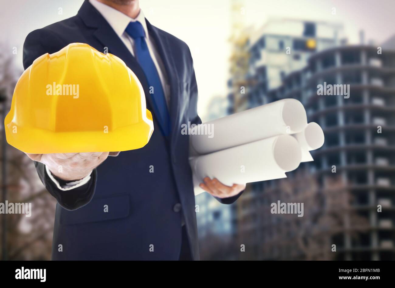 Engineer with blueprint on blurred construction site background Stock ...