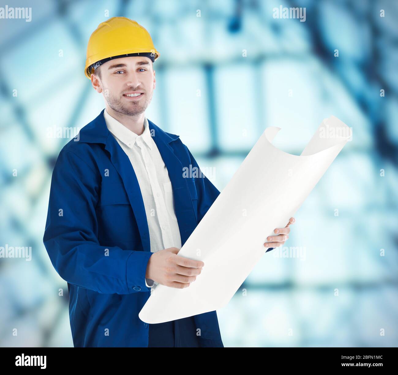 Professional engineer with blueprint on blurred construction background ...