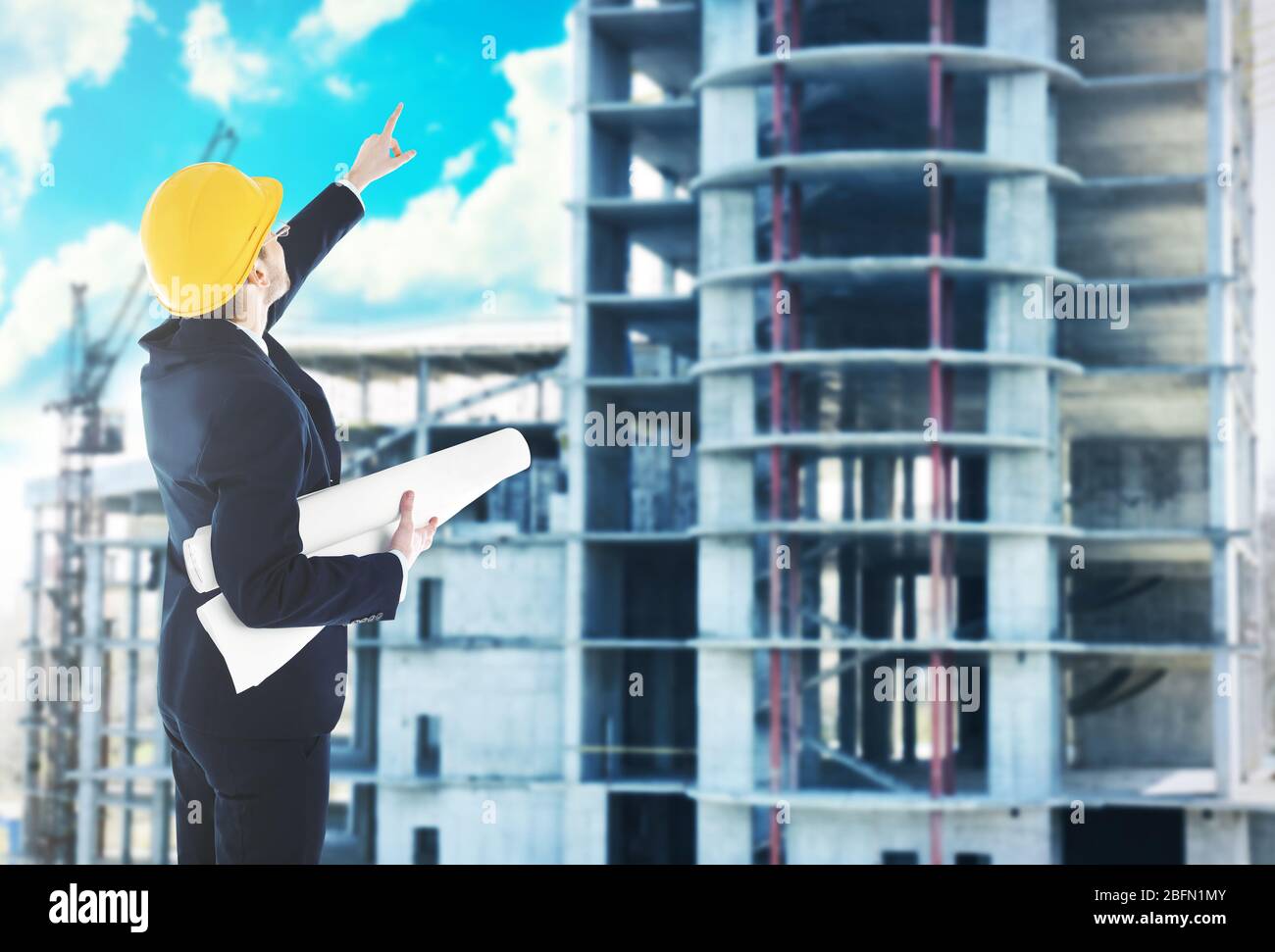 Professional engineer with blueprint on blurred construction site ...