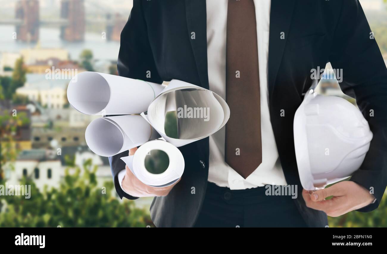 Engineer with blueprint on blurred urban background Stock Photo - Alamy